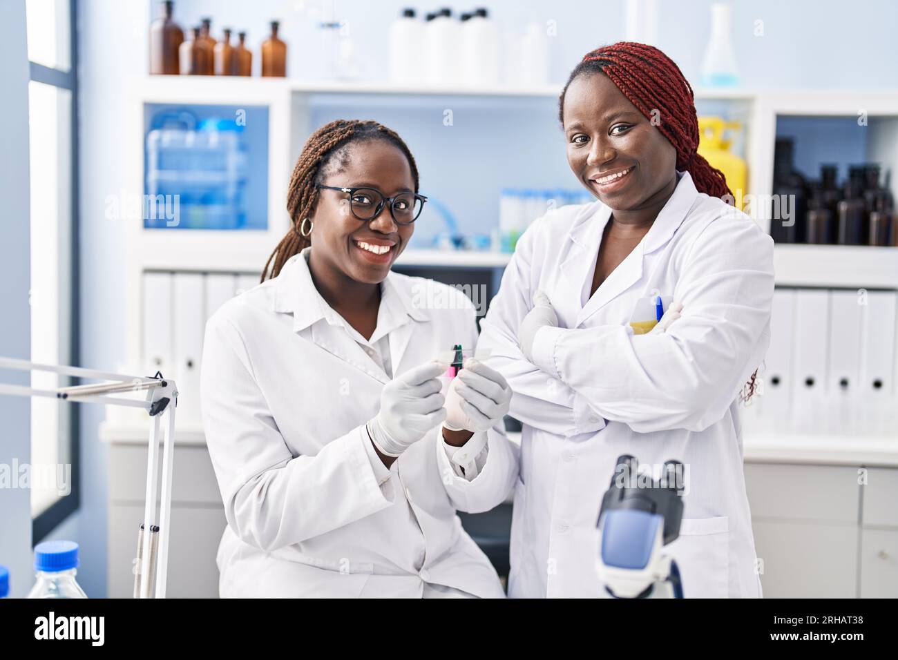 African american women scientists looking sample standing with arms crossed gesture at ...