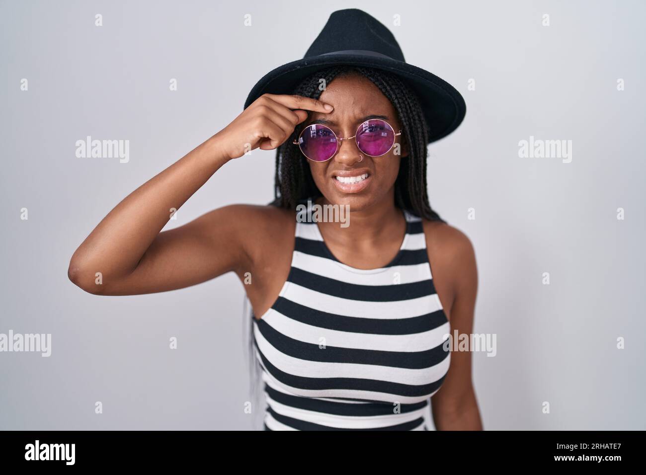 Young african american with braids wearing hat and sunglasses pointing ...