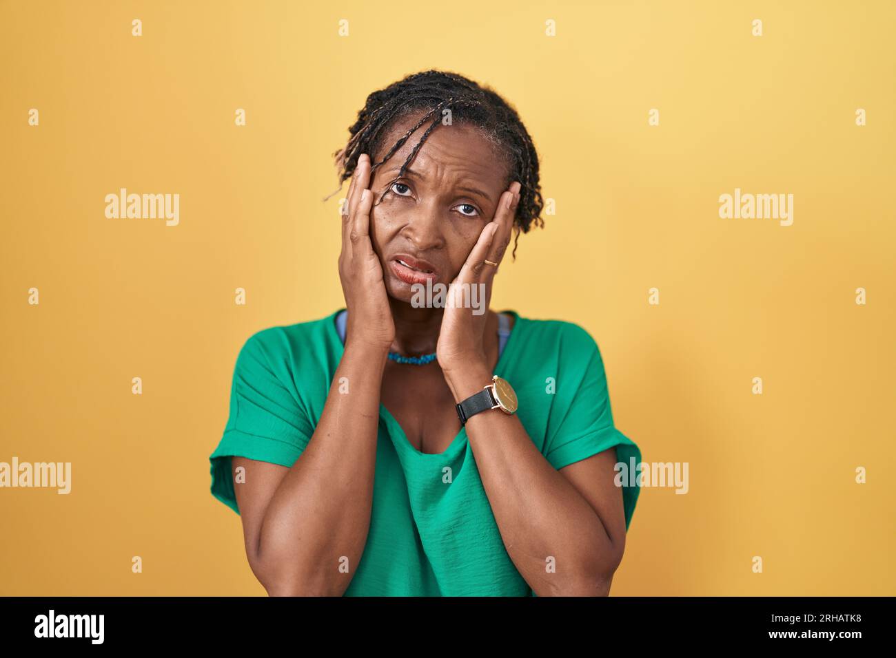 African woman with dreadlocks standing over yellow background tired ...
