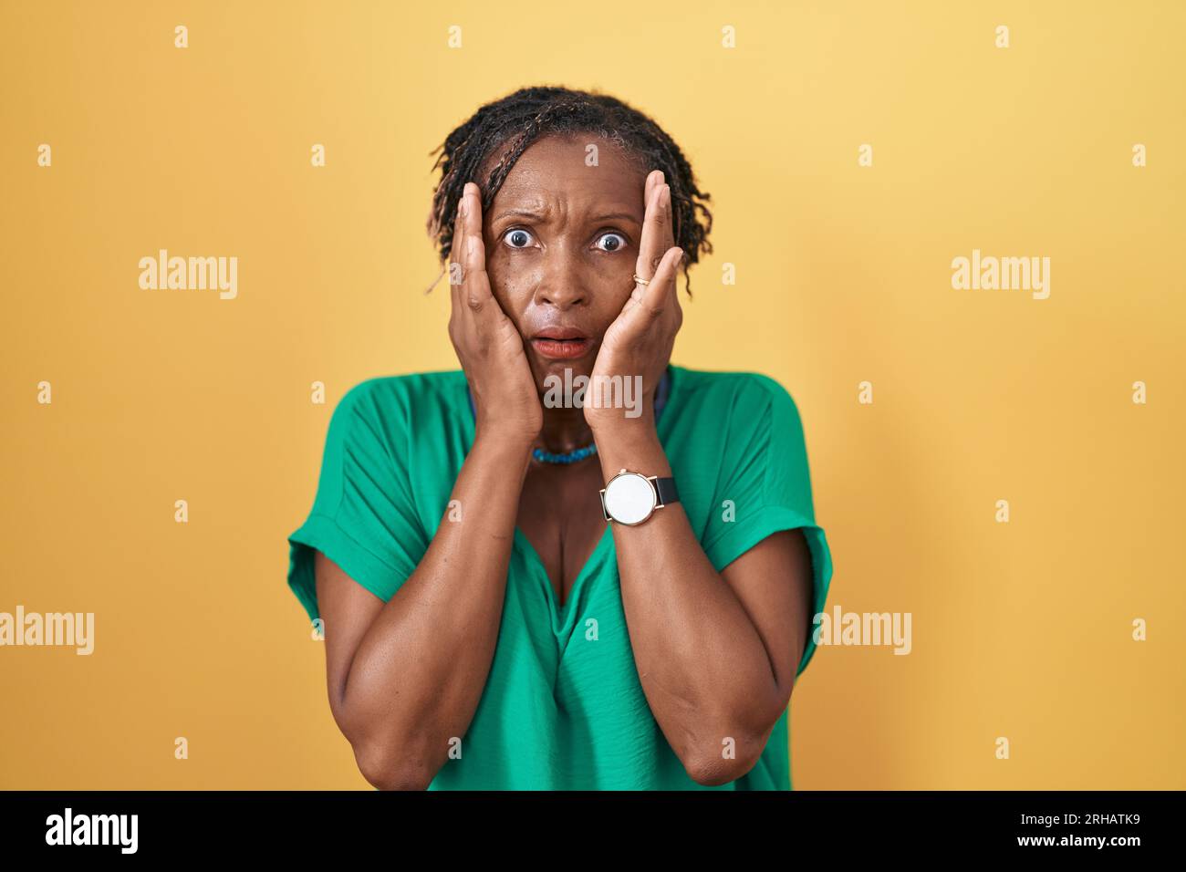 African woman with dreadlocks standing over yellow background afraid ...