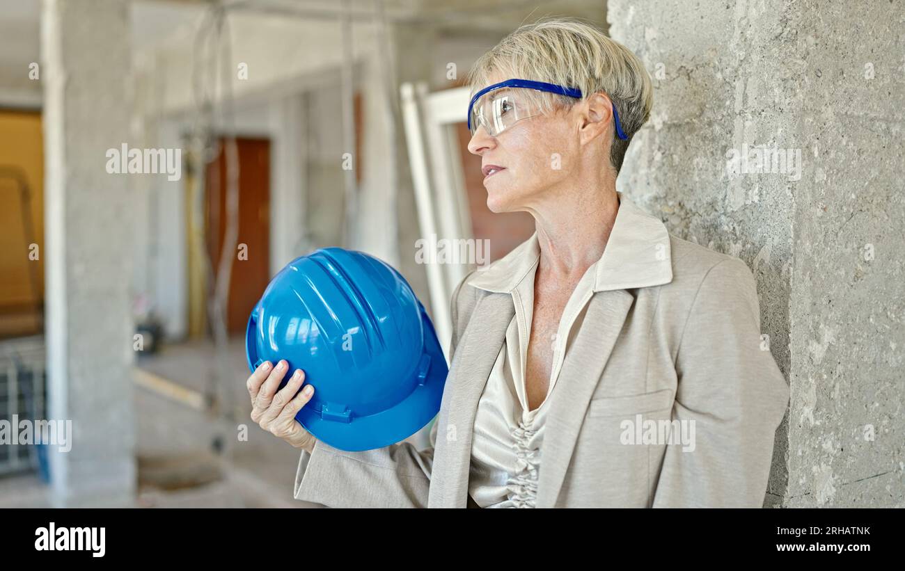 Middle age blonde woman architect standing with relaxed expression ...