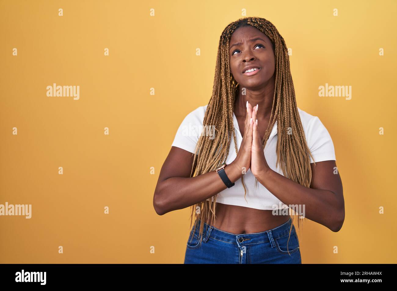 African american woman with braided hair standing over yellow ...