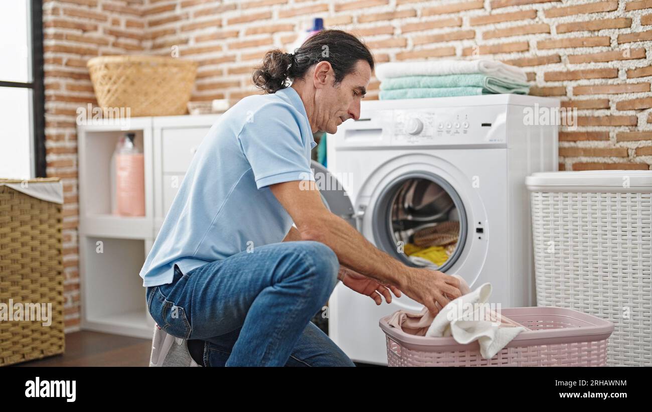 Middle age man washing clothes at laundry room Stock Photo - Alamy