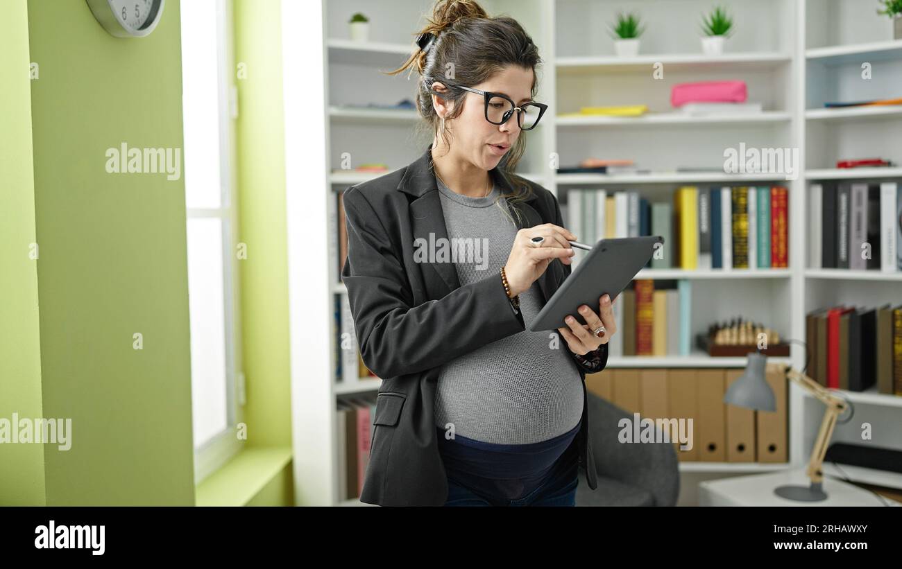 Young pregnant woman teacher using touchpad at library university Stock ...