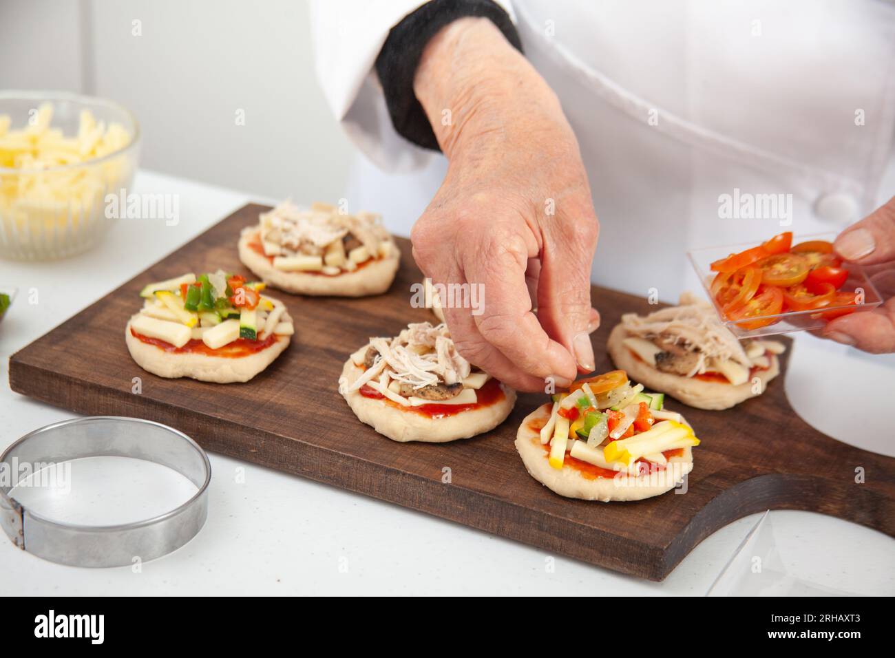 Adding toppings to the mini pizzas. Delicious homemade mini pizzas preparation Stock Photo - Alamy