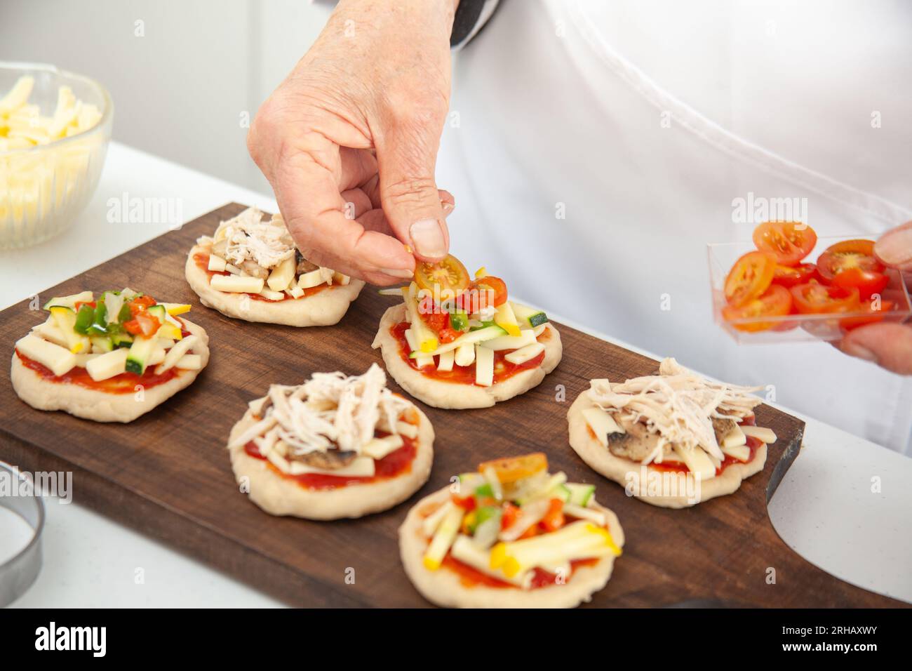 Adding toppings to the mini pizzas. Delicious homemade mini pizzas preparation Stock Photo - Alamy