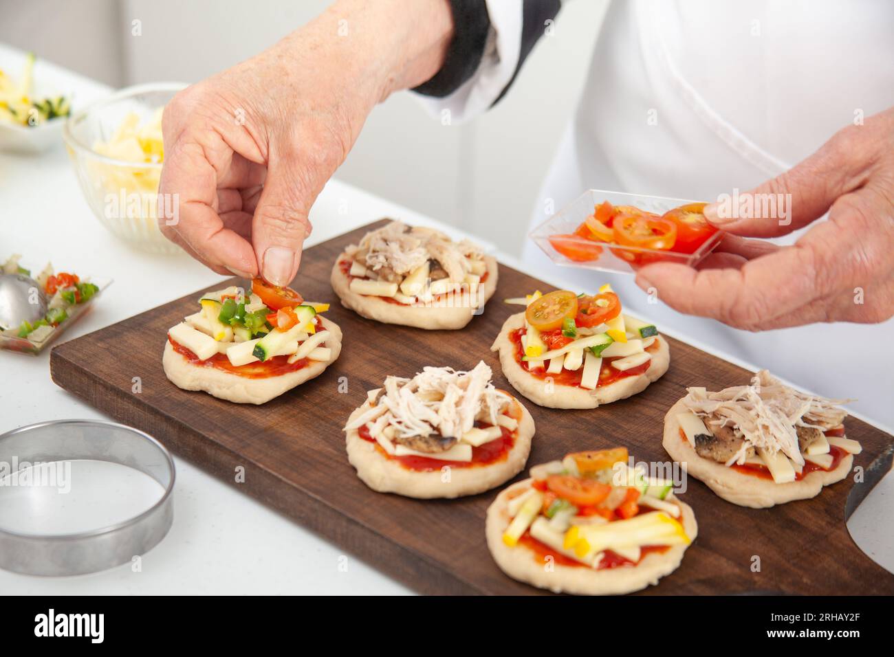 Adding toppings to the mini pizzas. Delicious homemade mini pizzas preparation Stock Photo - Alamy