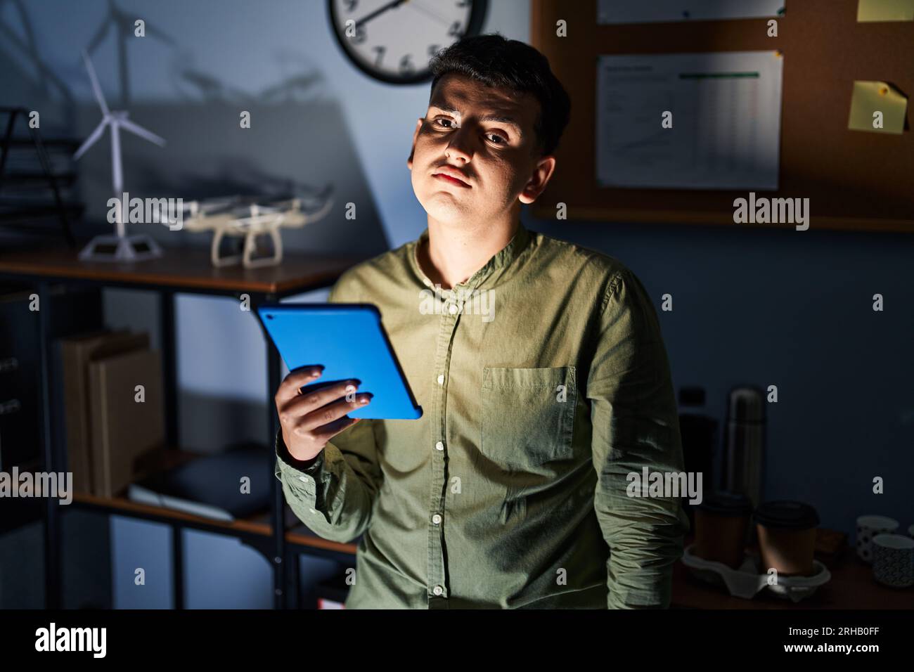 Non binary person using touchpad device at night looking sleepy and ...