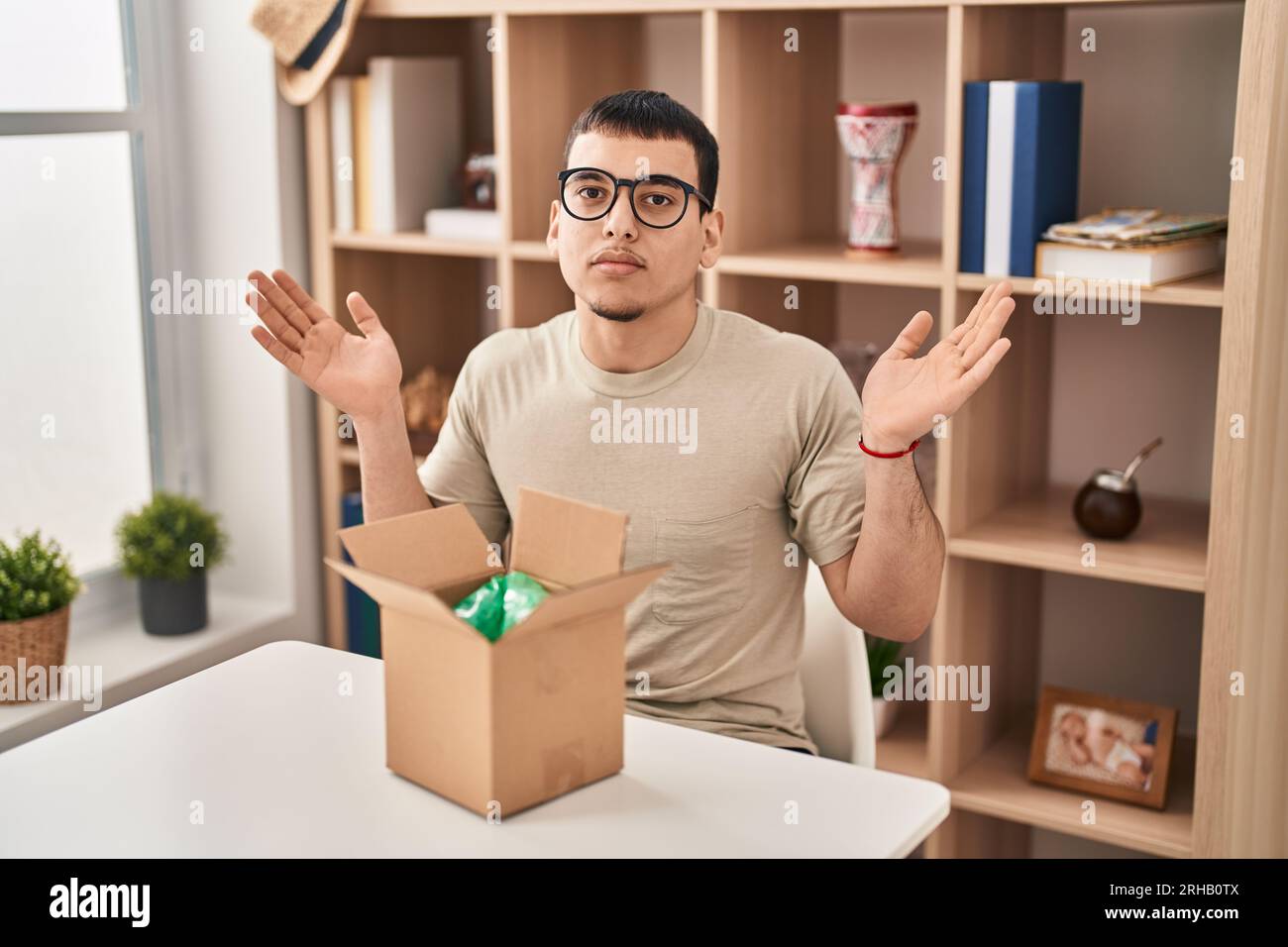 Young arab man with open gift in cardboard box shouting and screaming ...