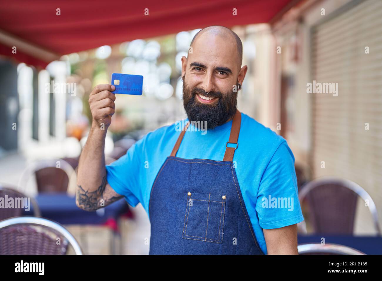 Young bald man waiter smiling confident holding credit card at coffee ...