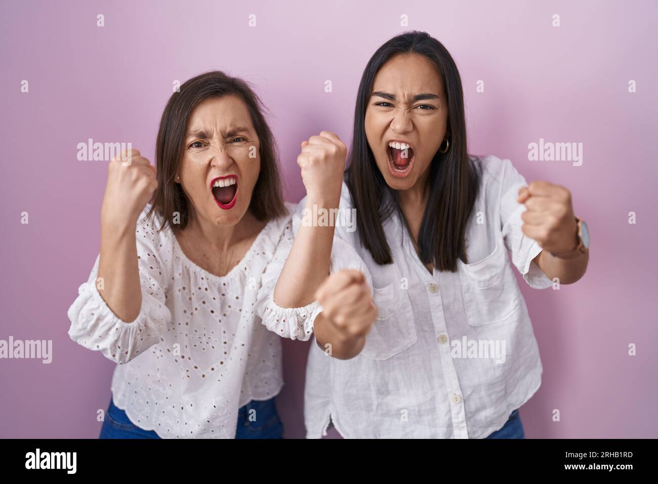 Hispanic mother and daughter together angry and mad raising fists ...