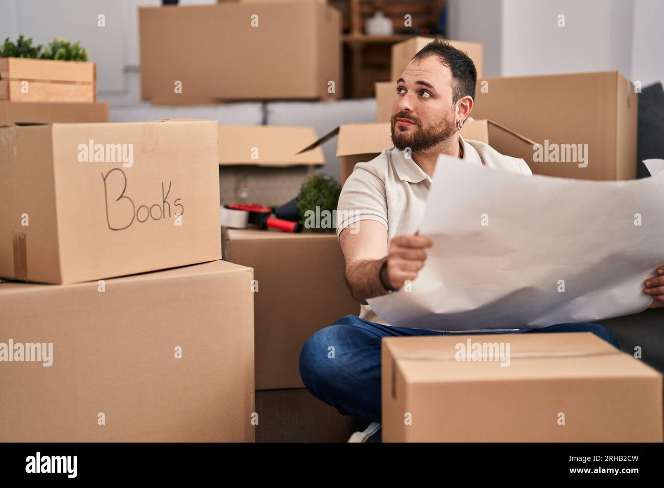 Young hispanic man looking house plans at new home Stock Photo - Alamy