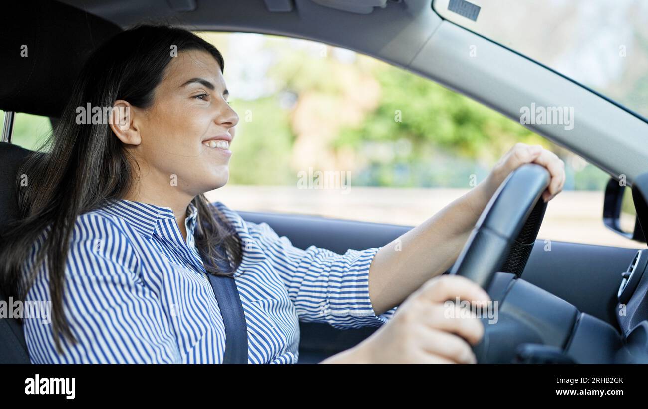 Young beautiful hispanic woman driving a car smiling on the road Stock ...