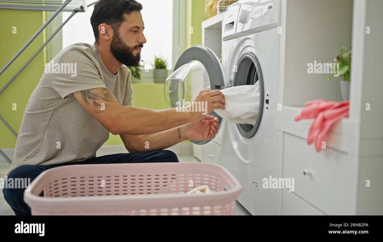 Young hispanic man washing clothes at laundry room Stock Photo - Alamy