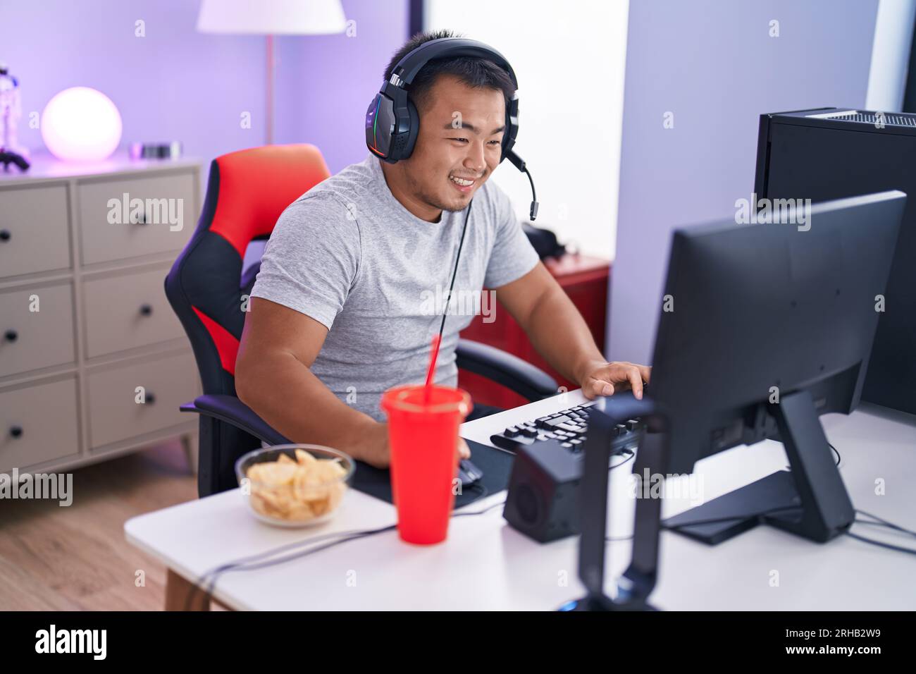 Young chinese man streamer playing video game using computer at gaming ...