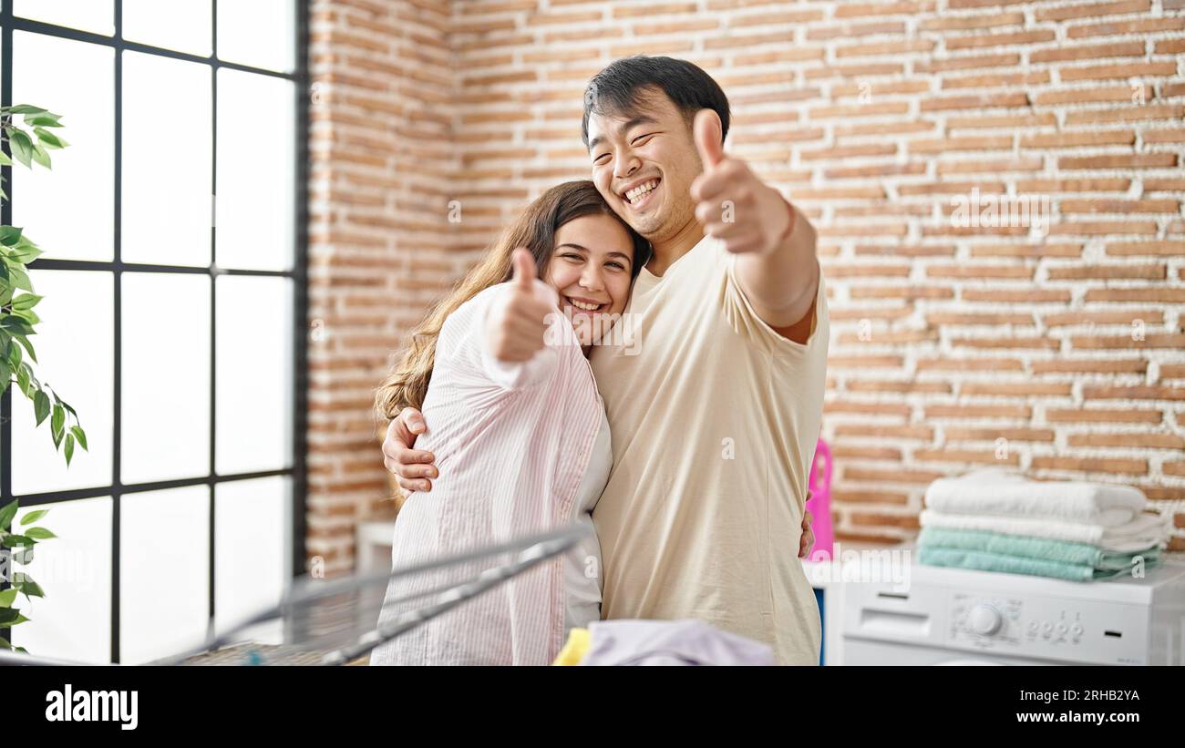Man and woman couple smiling confident doing thumbs up gesture at laundry room Stock Photo - Alamy