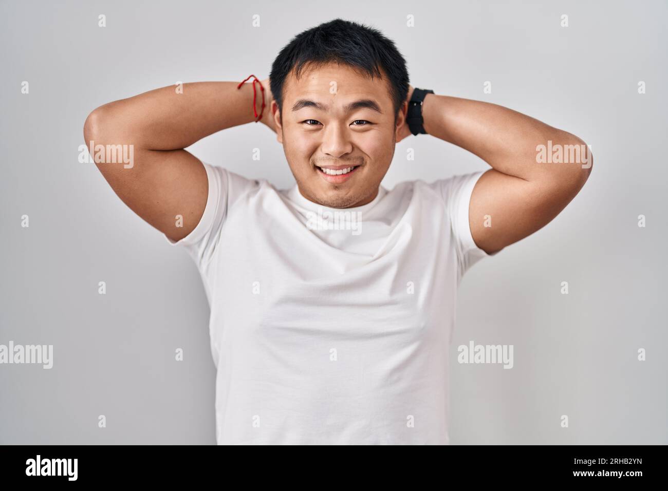 Young chinese man standing over white background relaxing and ...