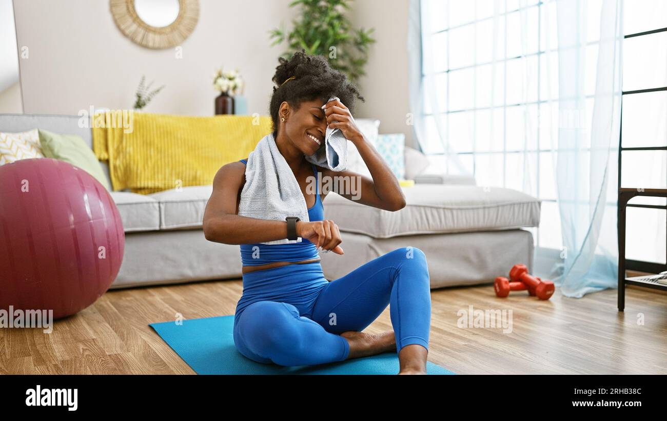 African american woman wearing sportswear looking watch sweating at ...