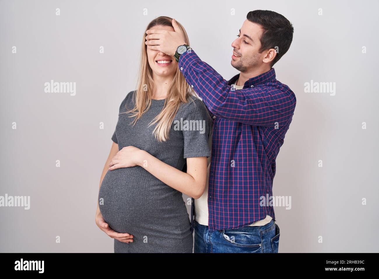Young couple expecting a baby standing over white background smiling ...