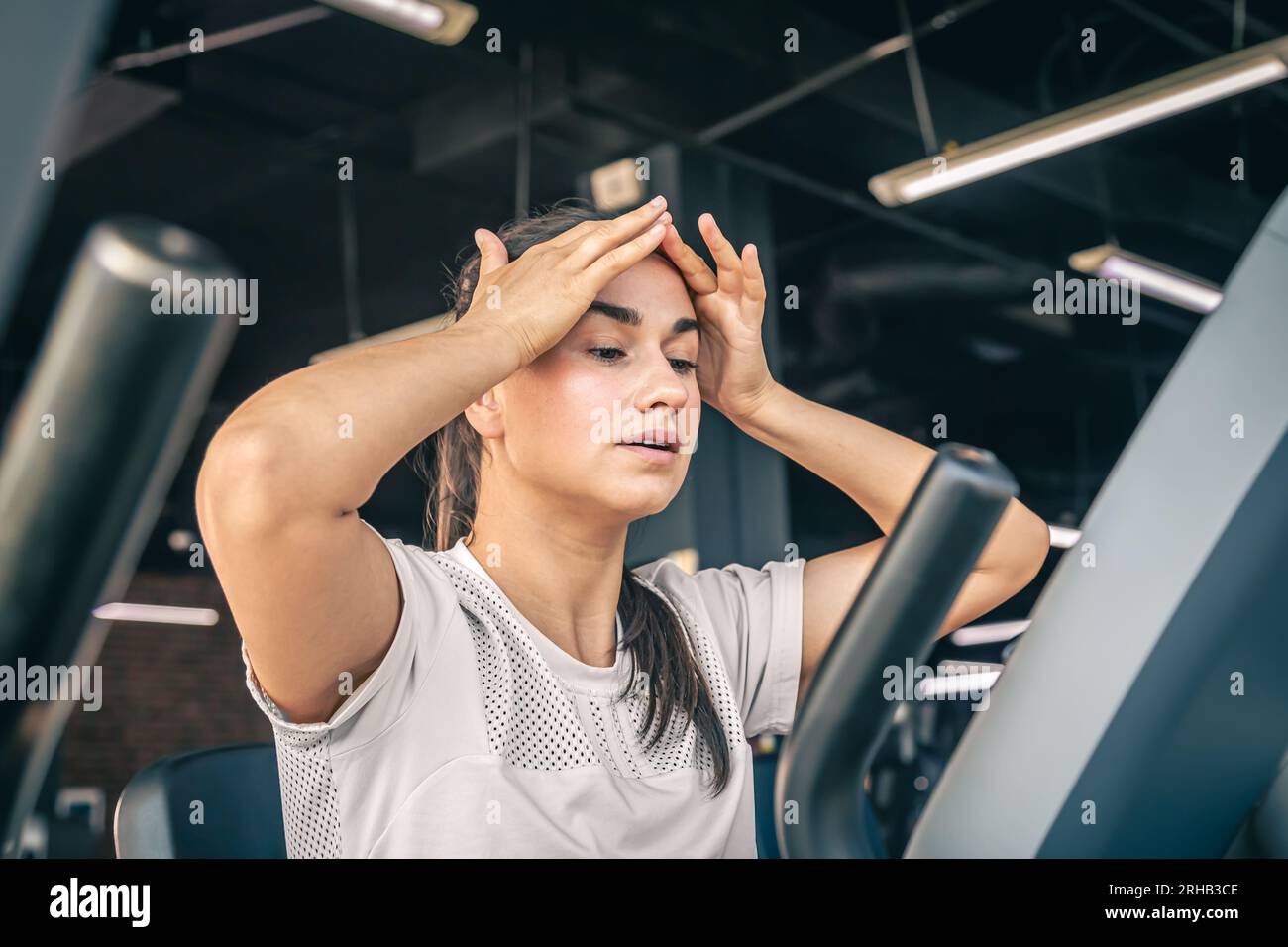 A young woman tired after intense workout on the exercise bike at the ...