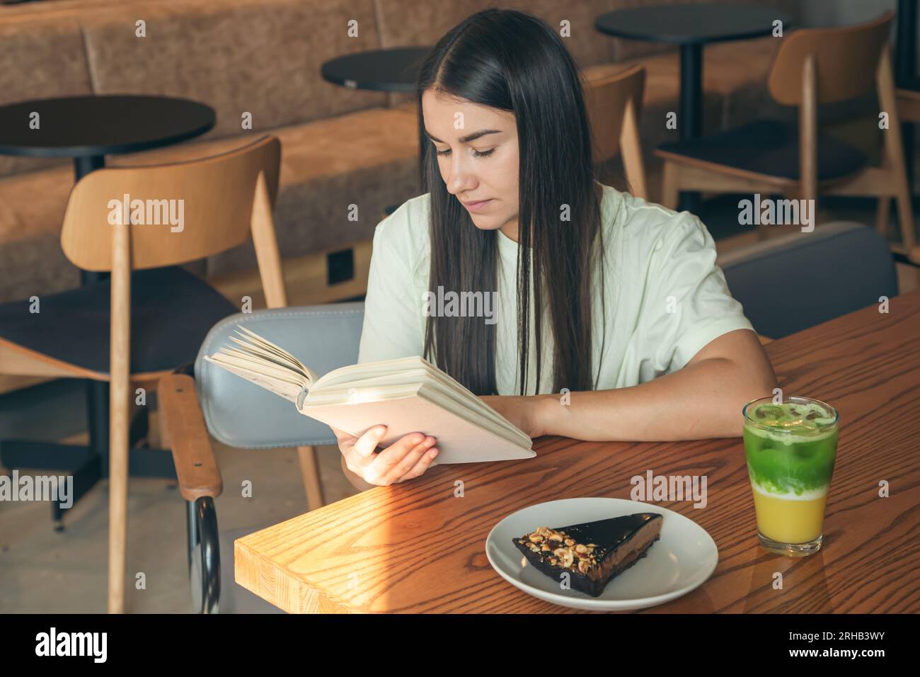 Attractive young woman is reading a book while sitting in a cafe Stock ...