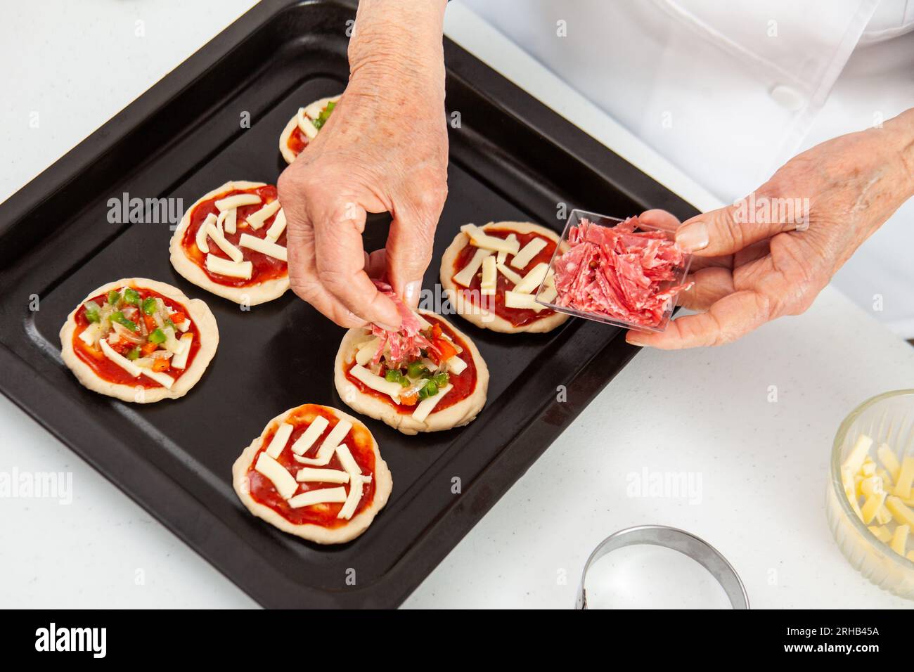 Adding toppings to the mini pizzas. adding salami. Delicious homemade mini pizzas preparation ...