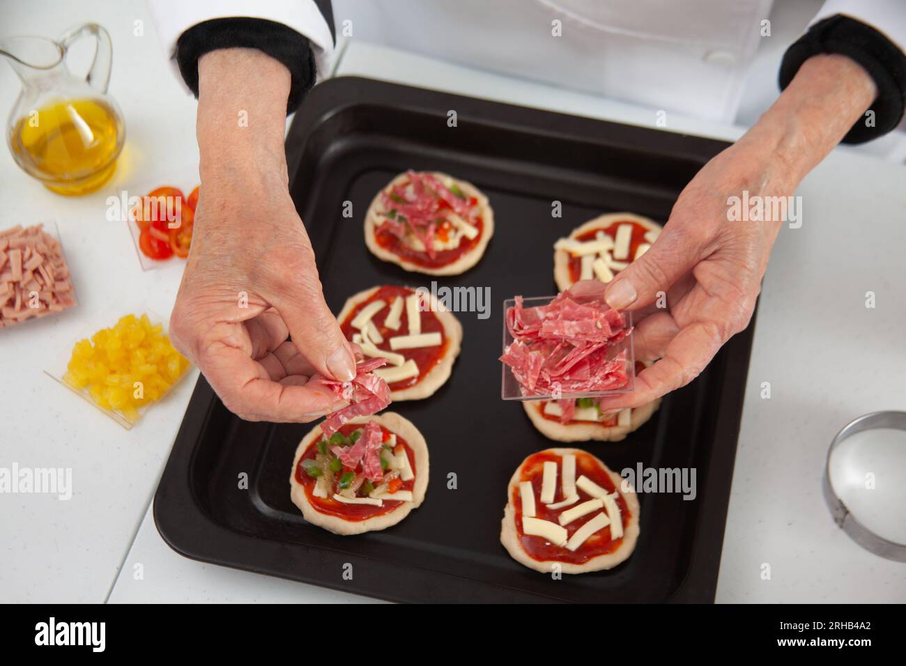 Adding toppings to the mini pizzas. adding salami. Delicious homemade mini pizzas preparation ...