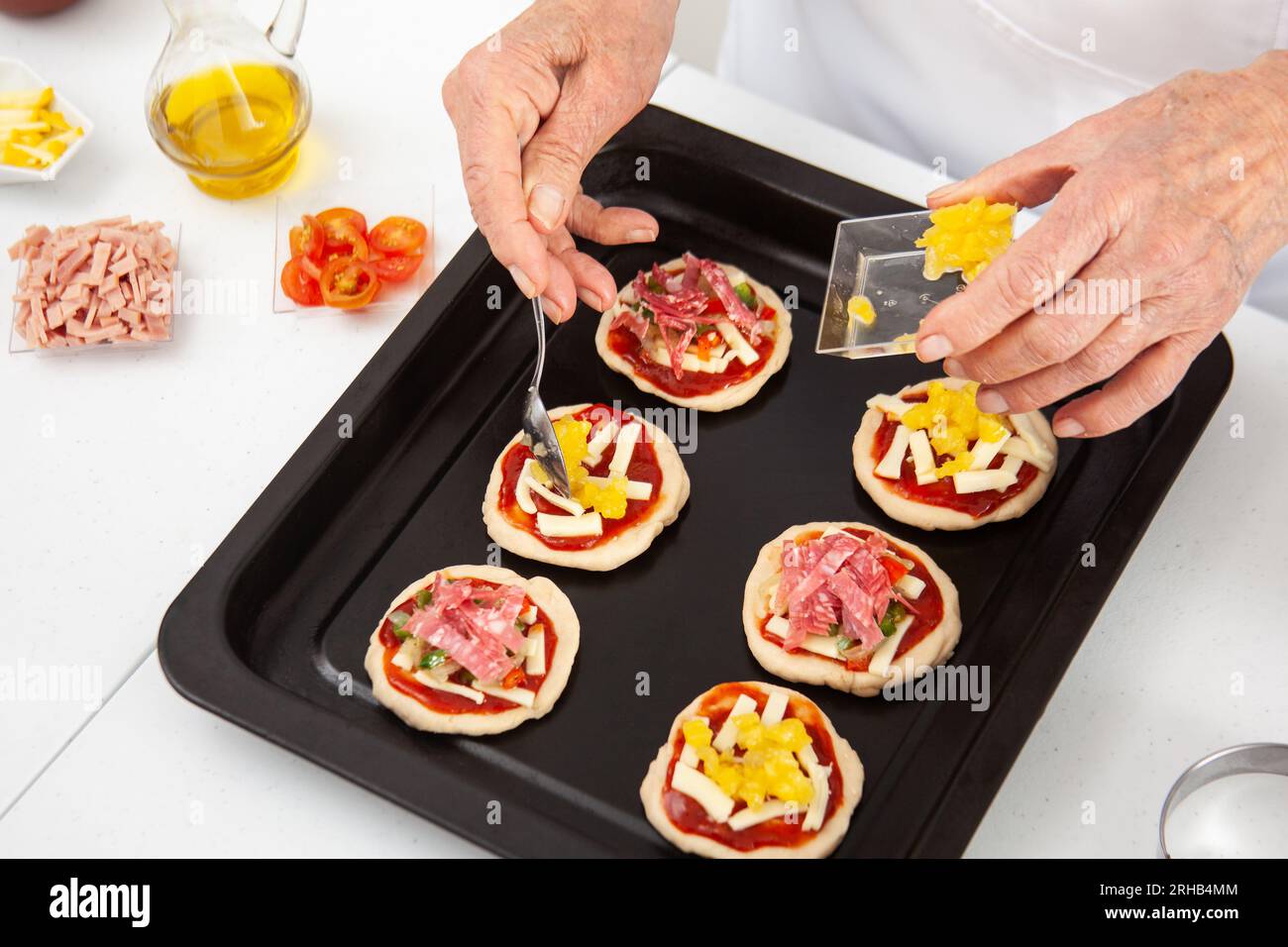 Adding toppings to the mini pizzas. Adding pineapple to the Hawaiian ...