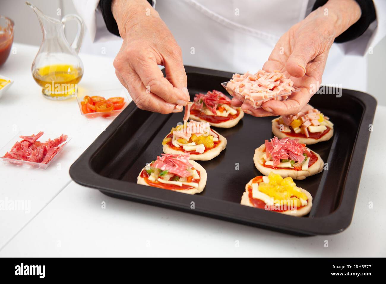 Adding toppings to the mini pizzas. Adding ham to the Hawaiian pizza ...