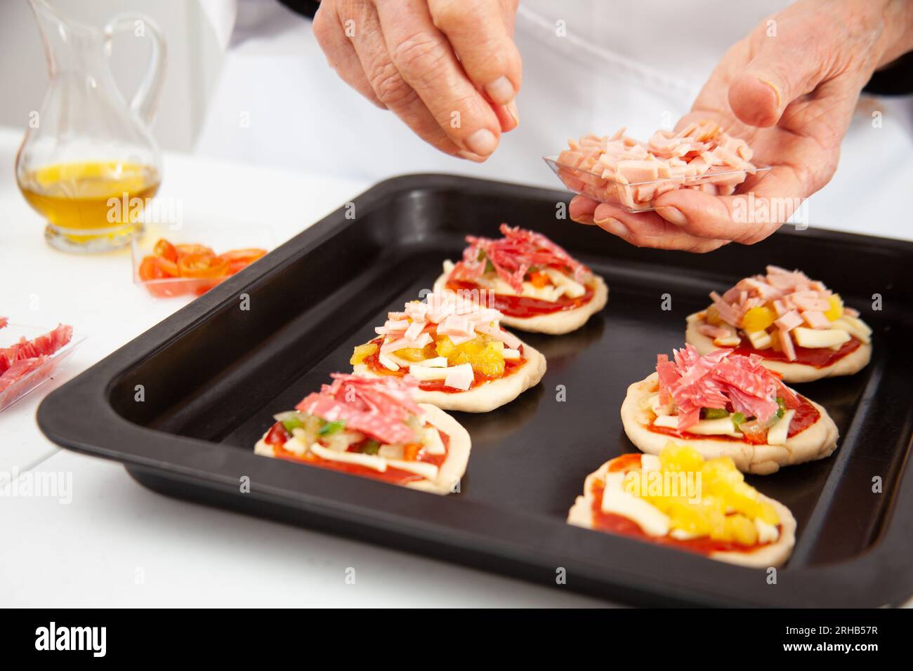 Adding toppings to the mini pizzas. Adding ham to the Hawaiian pizza. Delicious homemade mini ...