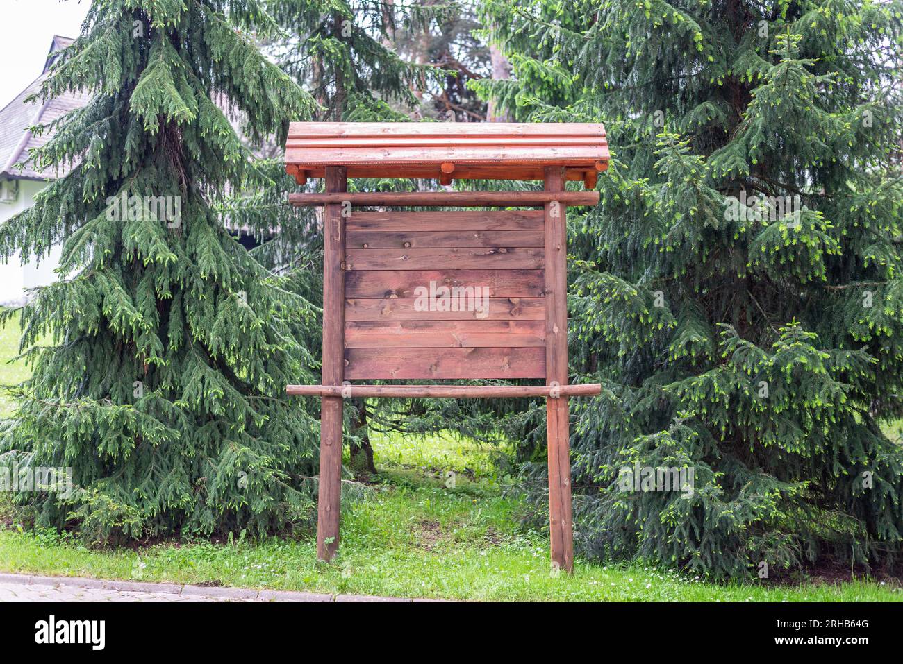 Rustic wooden billboard on pillars for information with lush pines ...