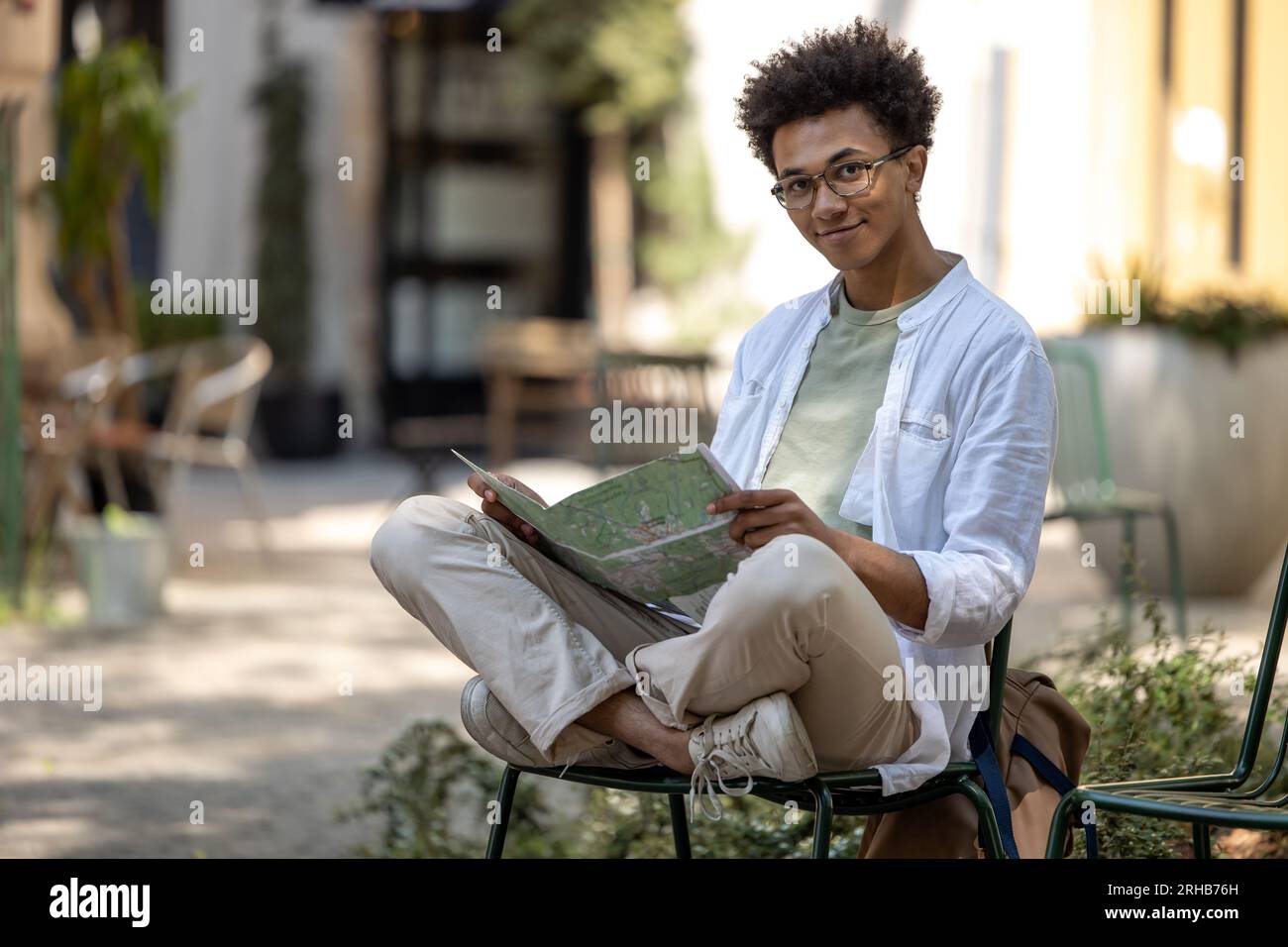 Young curly-haired tourist with a map in hands Stock Photo - Alamy