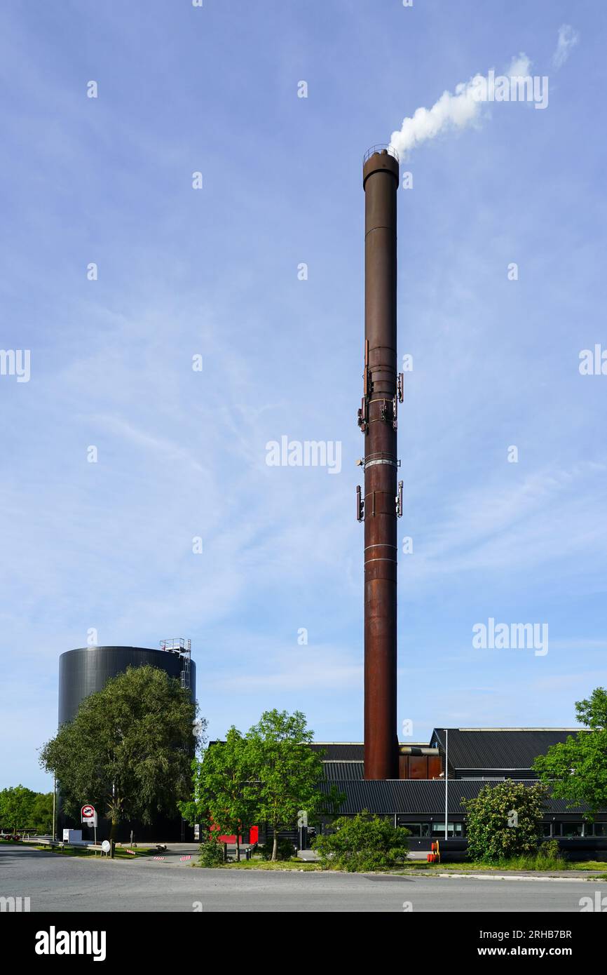 Modern factory with a tall rusty chimney from which comes out white ...