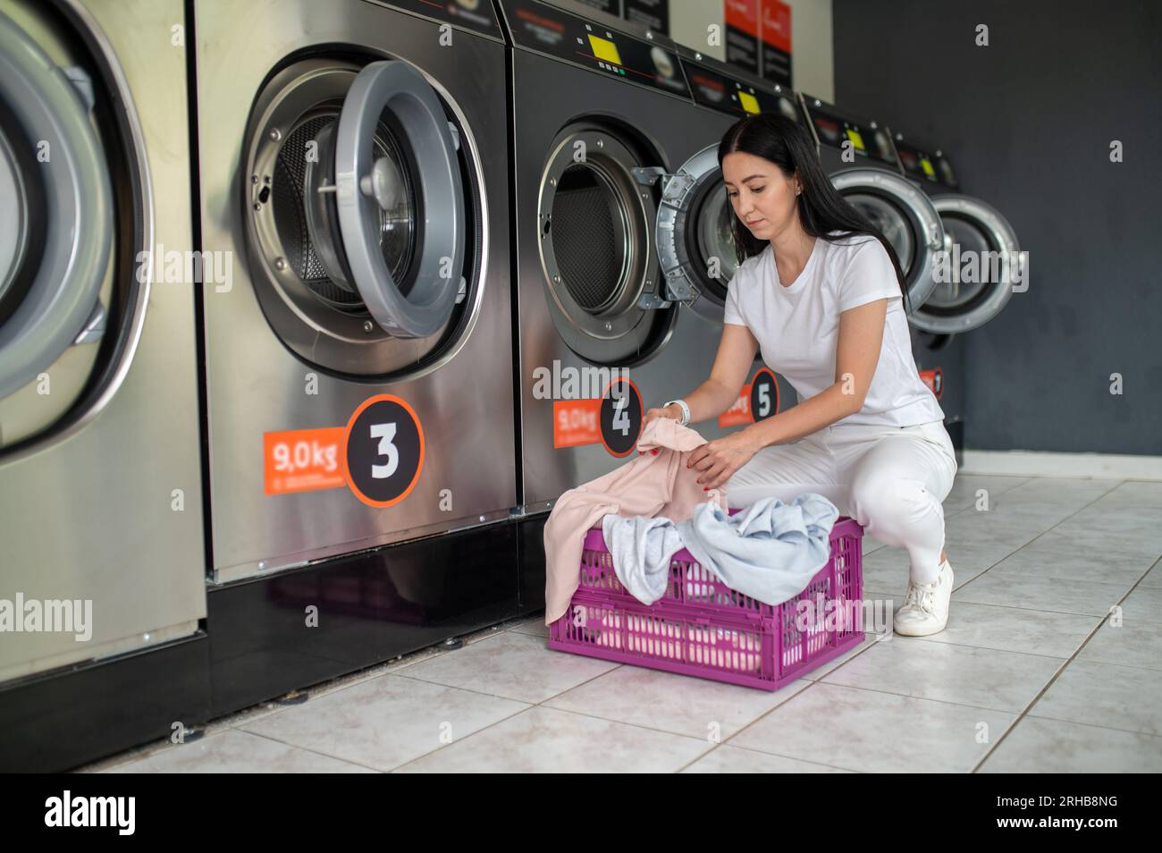 Young brunette woman sorting clothes in laundromat in the laundry Stock ...
