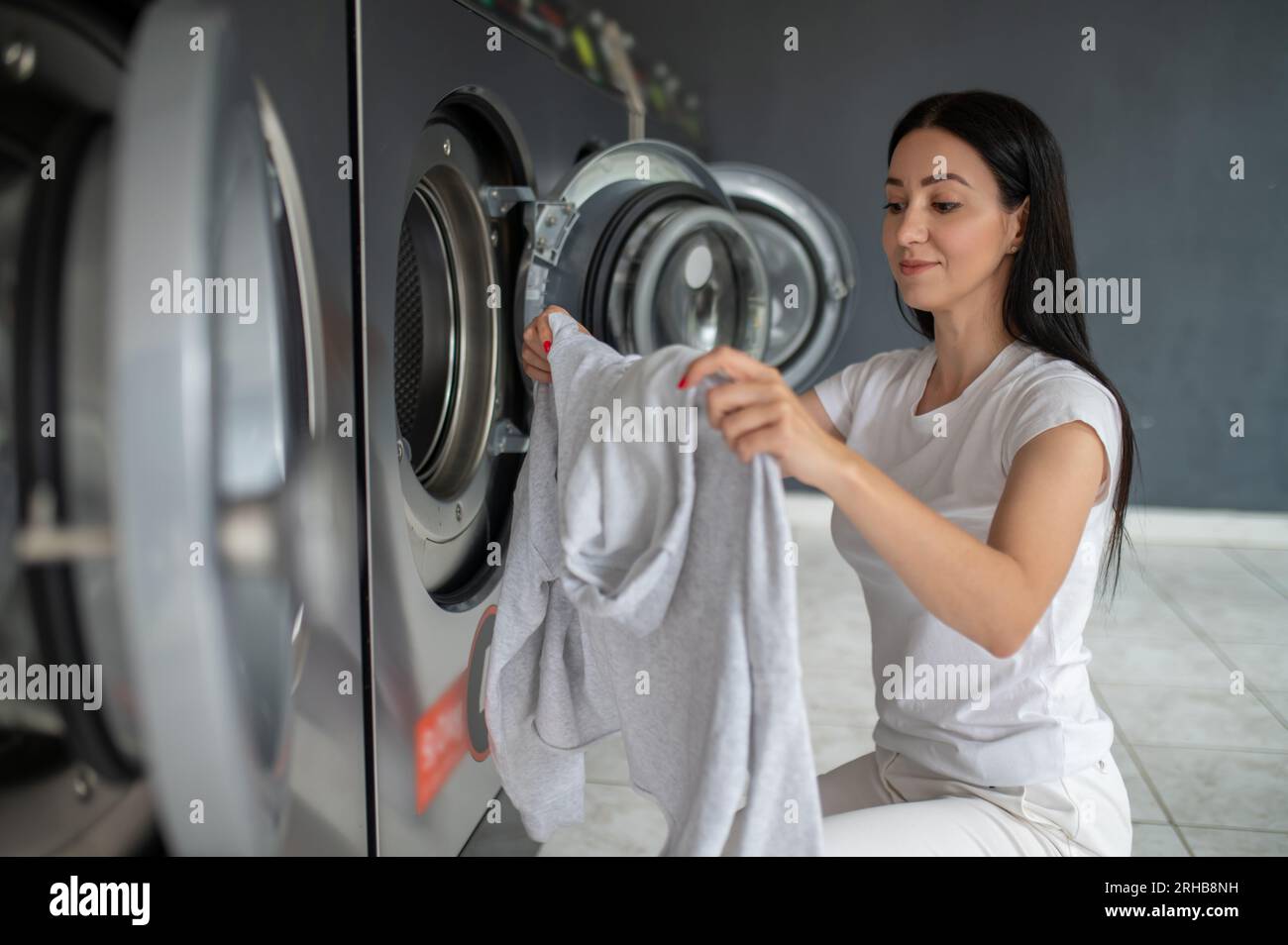 Young brunette woman sorting clothes in laundromat in the laundry Stock ...