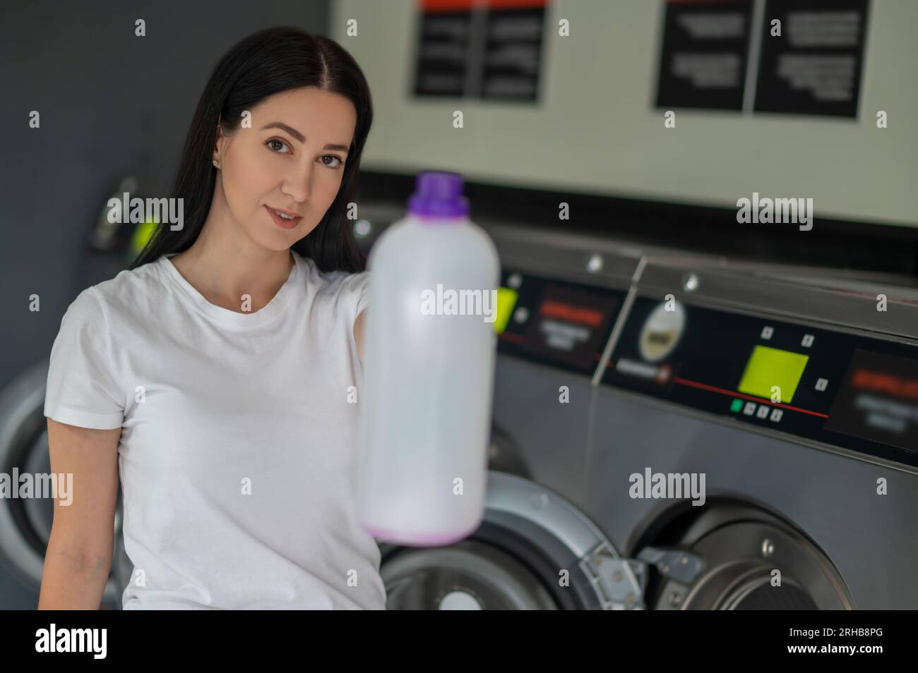 Young woman holding detergent using washing machine Stock Photo - Alamy