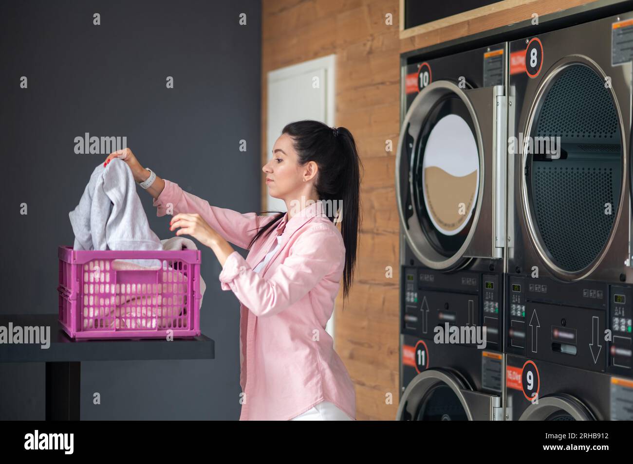 Young woman unloading washing machine in public laundry Stock Photo - Alamy