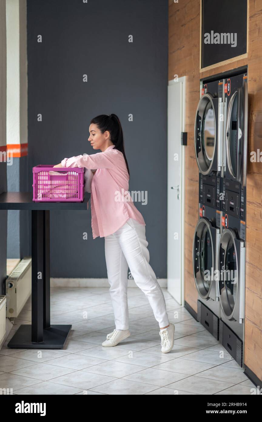 Young woman unloading washing machine in public laundry Stock Photo - Alamy