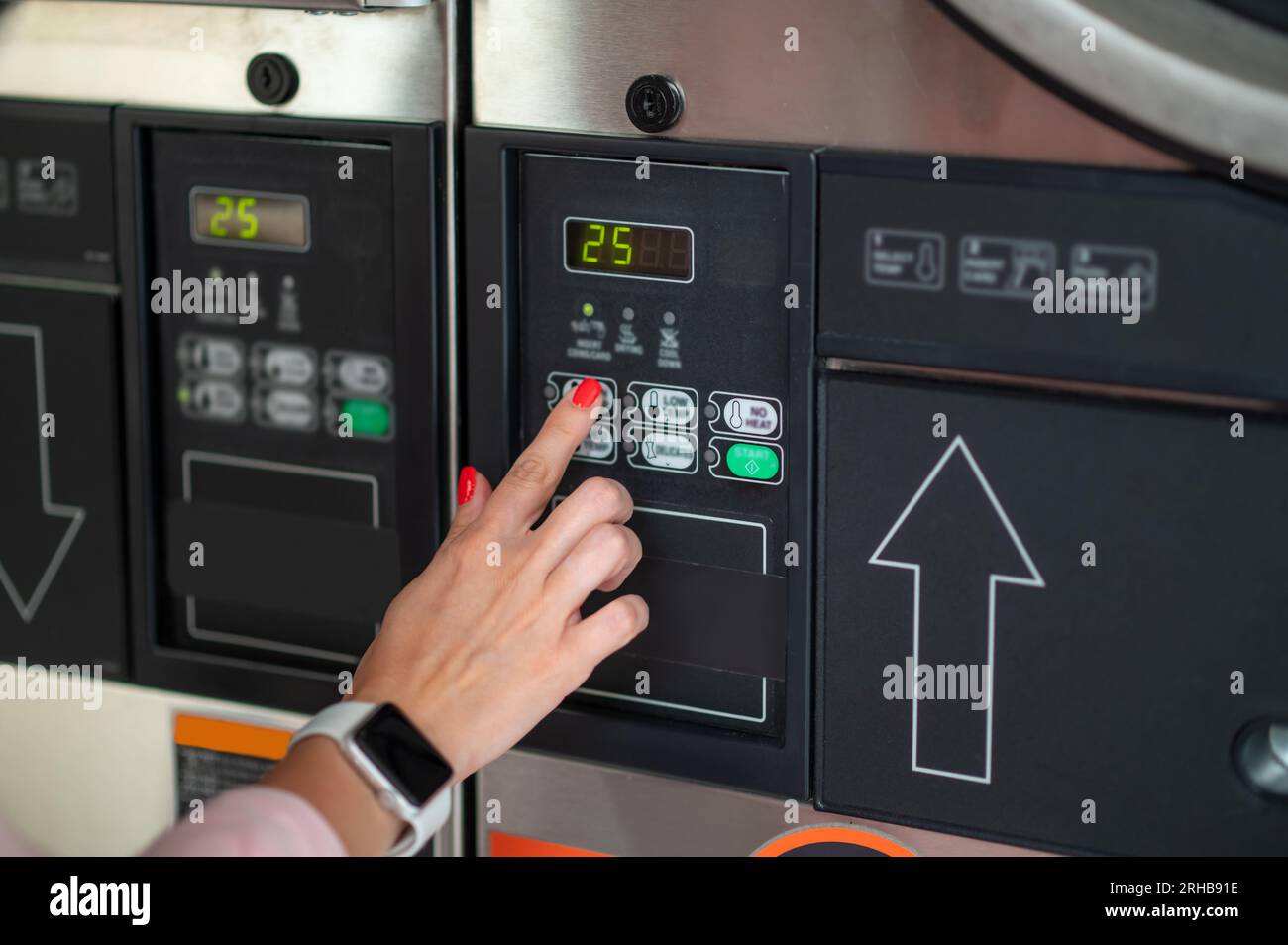 Young woman pressing button in washing machine at public laundry Stock ...