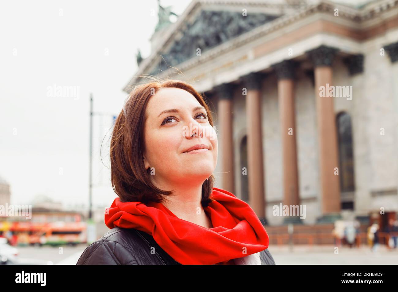 Positive young female woman 38 years old in red scarf looks up dreamily ...