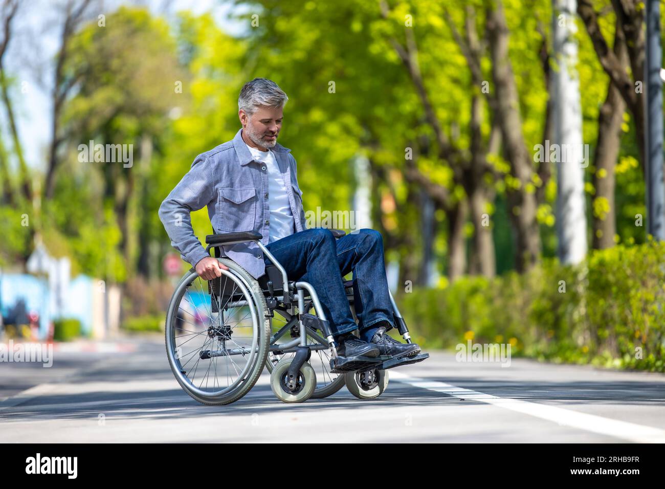 Handicapped man in wheelchair riding on street road, outdoor leisure ...