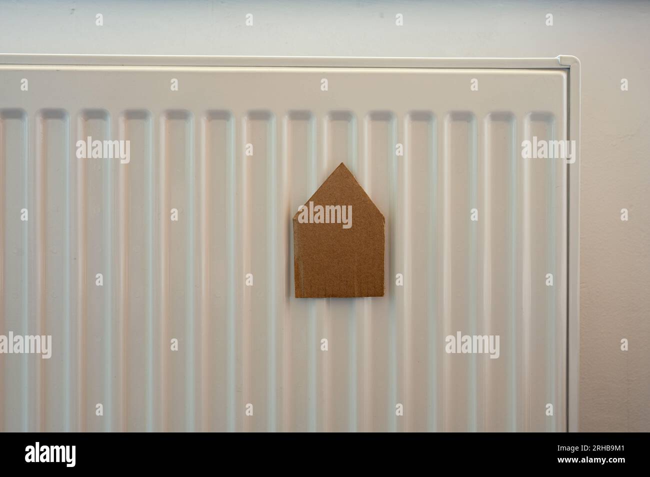 Paper carton house on the white radiator. Housing, energy, economy ...