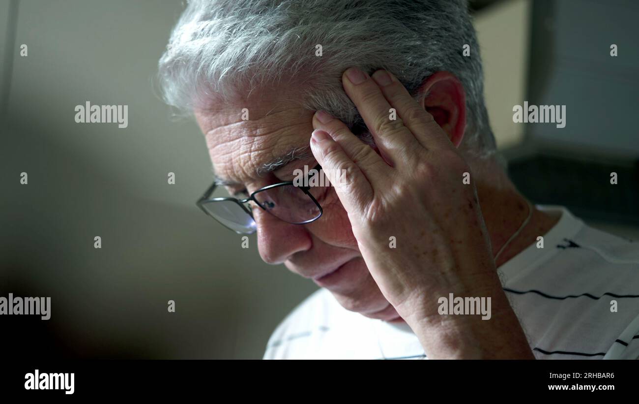 Preoccupied senior man feeling nervous reading content. Candid close-up ...