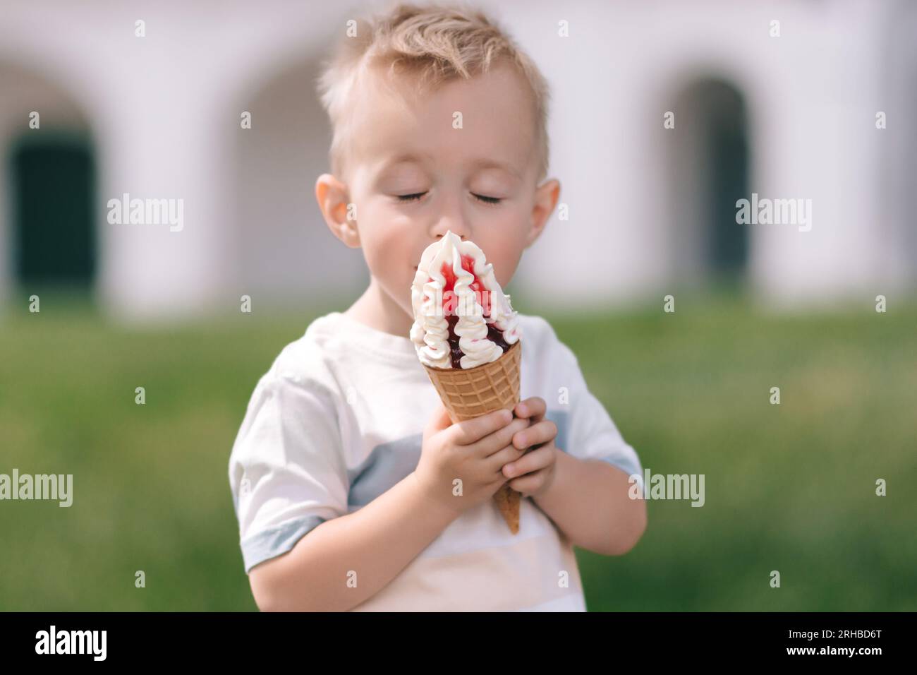 Portrait of a little boy. A baby eats a delicious ice cream cone. Happy ...
