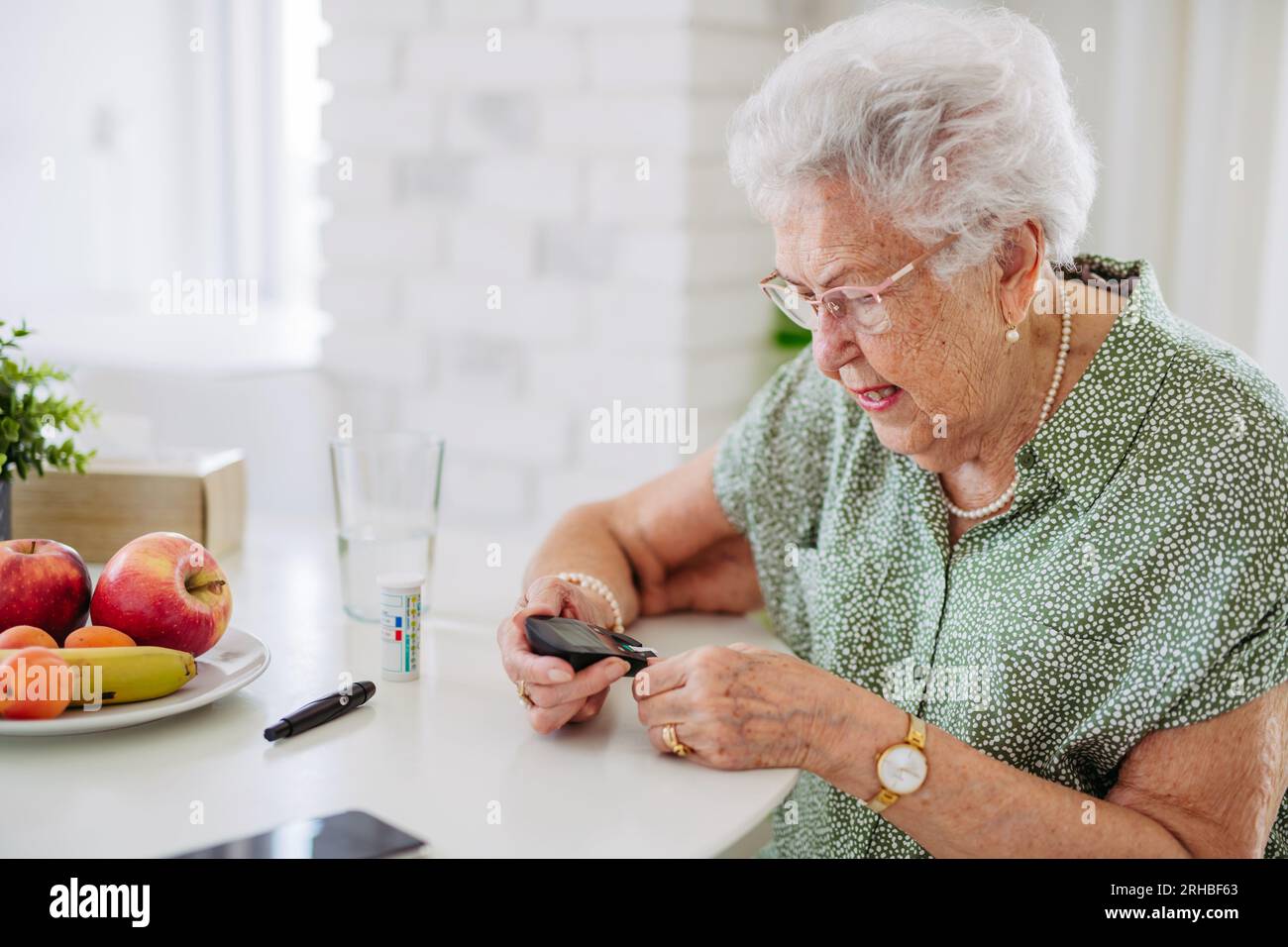 Diabetic senior patient checking her blood sugar level with fingerstick ...