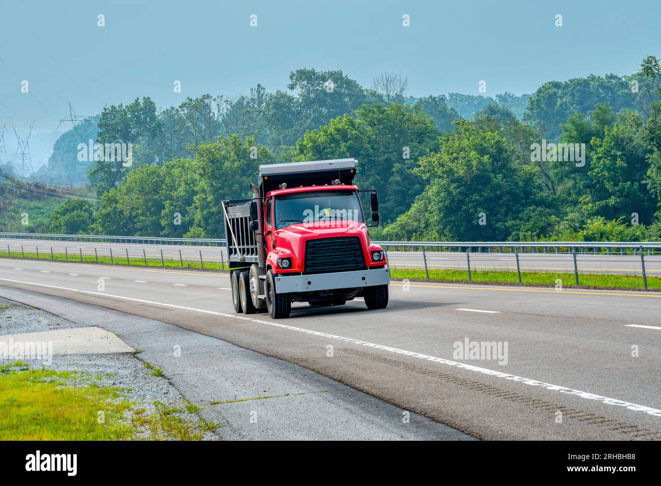 Horizontal shot of a heavy duty red dump truck on a hazy summer day ...