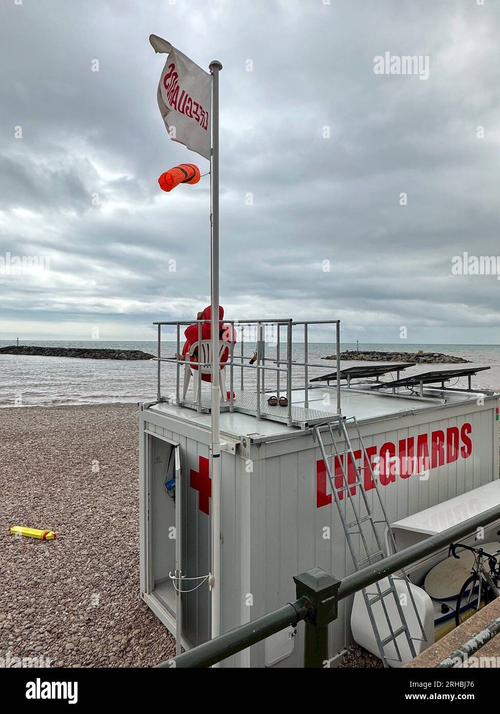 Lifeguard sitting on a lifeguard station in stormy weather, Sidmouth ...