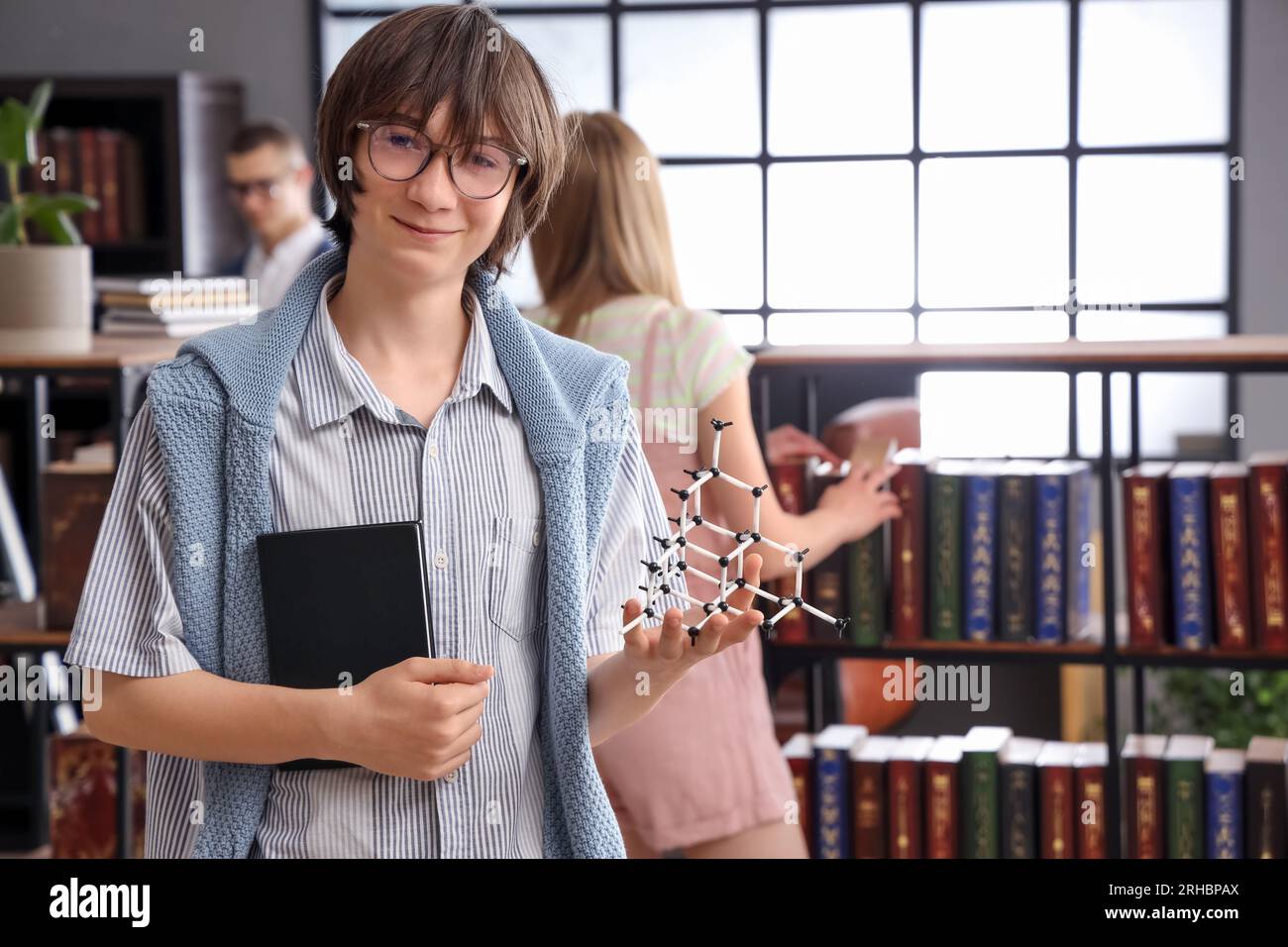 Male student with book and molecular model in library Stock Photo - Alamy