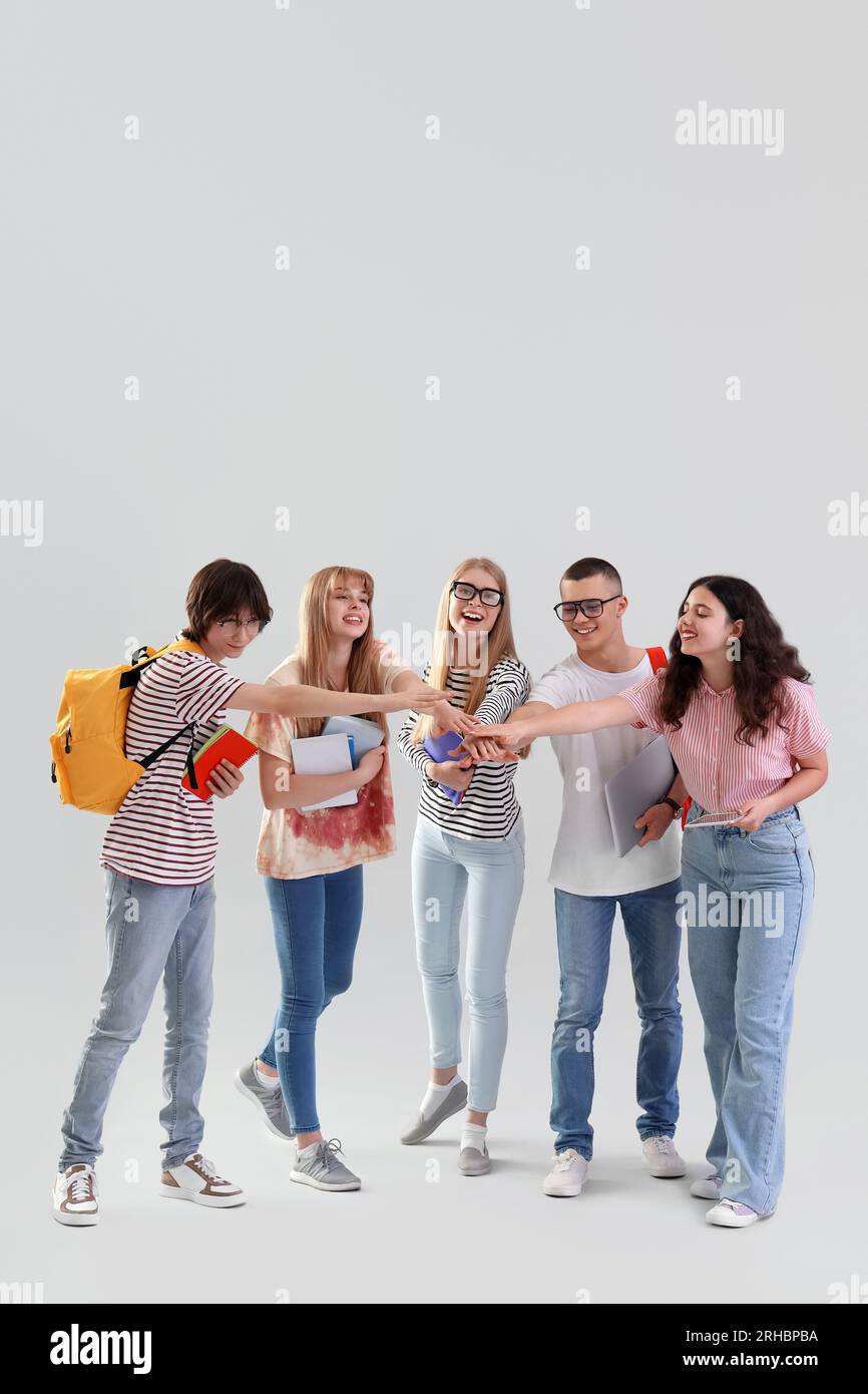 Group of students putting hands together on light background Stock ...