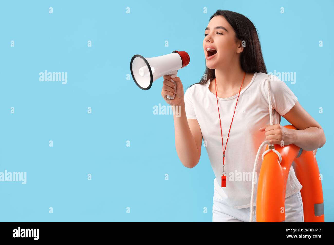 Female lifeguard with ring buoy shouting into megaphone on blue ...